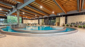 Uma grande piscina interior com vários níveis e áreas de descanso.