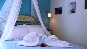 Uma cama com dossel, uma rosa vermelha e duas toalhas em forma de cisne.