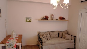Um quarto acolhedor com uma mesa de jantar de madeira, um sofá, um candelabro e uma prateleira com objetos decorativos.