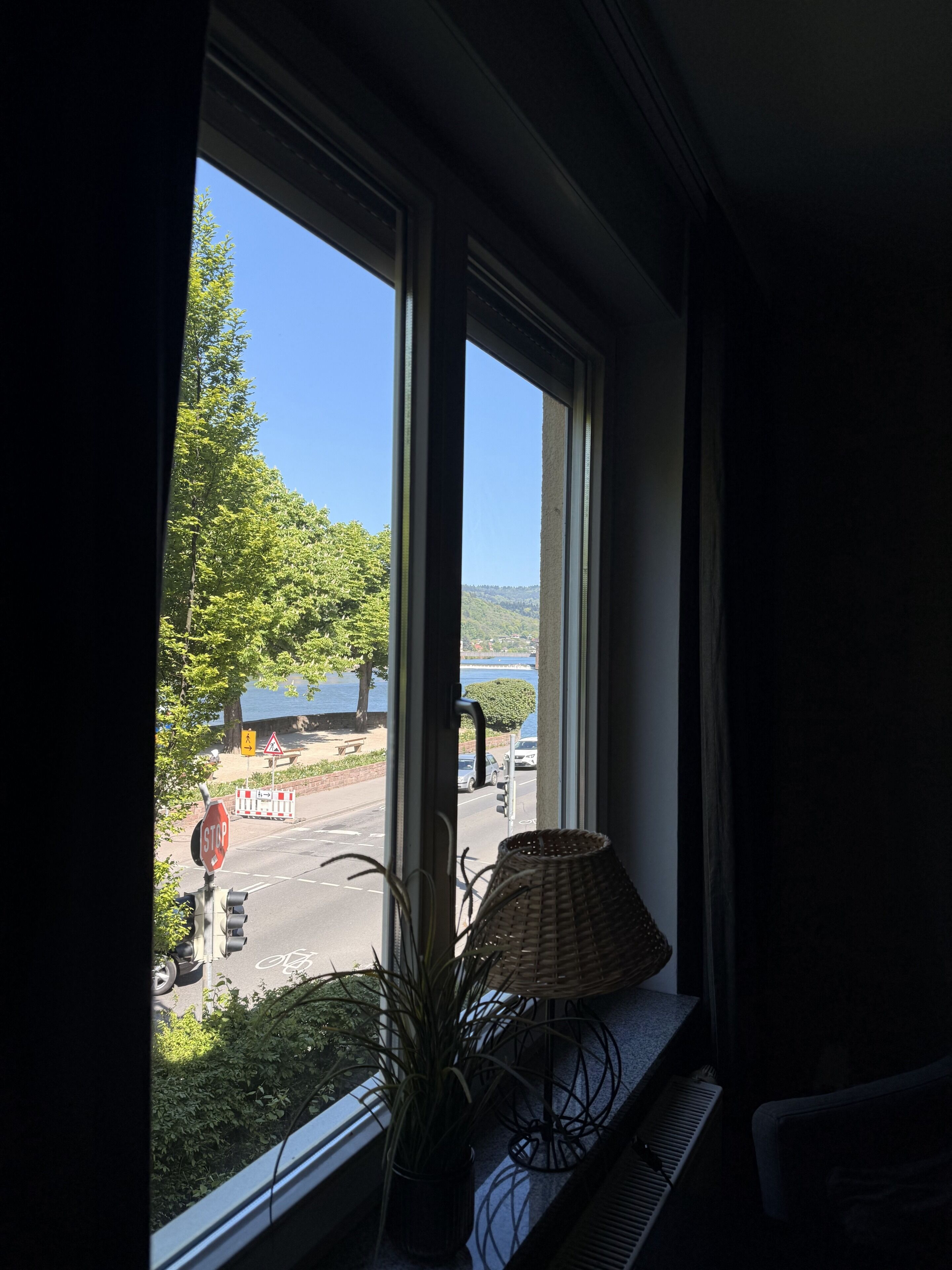Vista pela janela, com um sinal de parada, uma faixa de pedestres e uma cesta no parapeito.