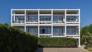 Um edifício com várias andares, varandas, janelas amplas e céu claro.