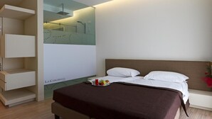 Quarto de hotel moderno com uma cama, uma pequena mesa com café da manhã e um espelho fixado na parede.