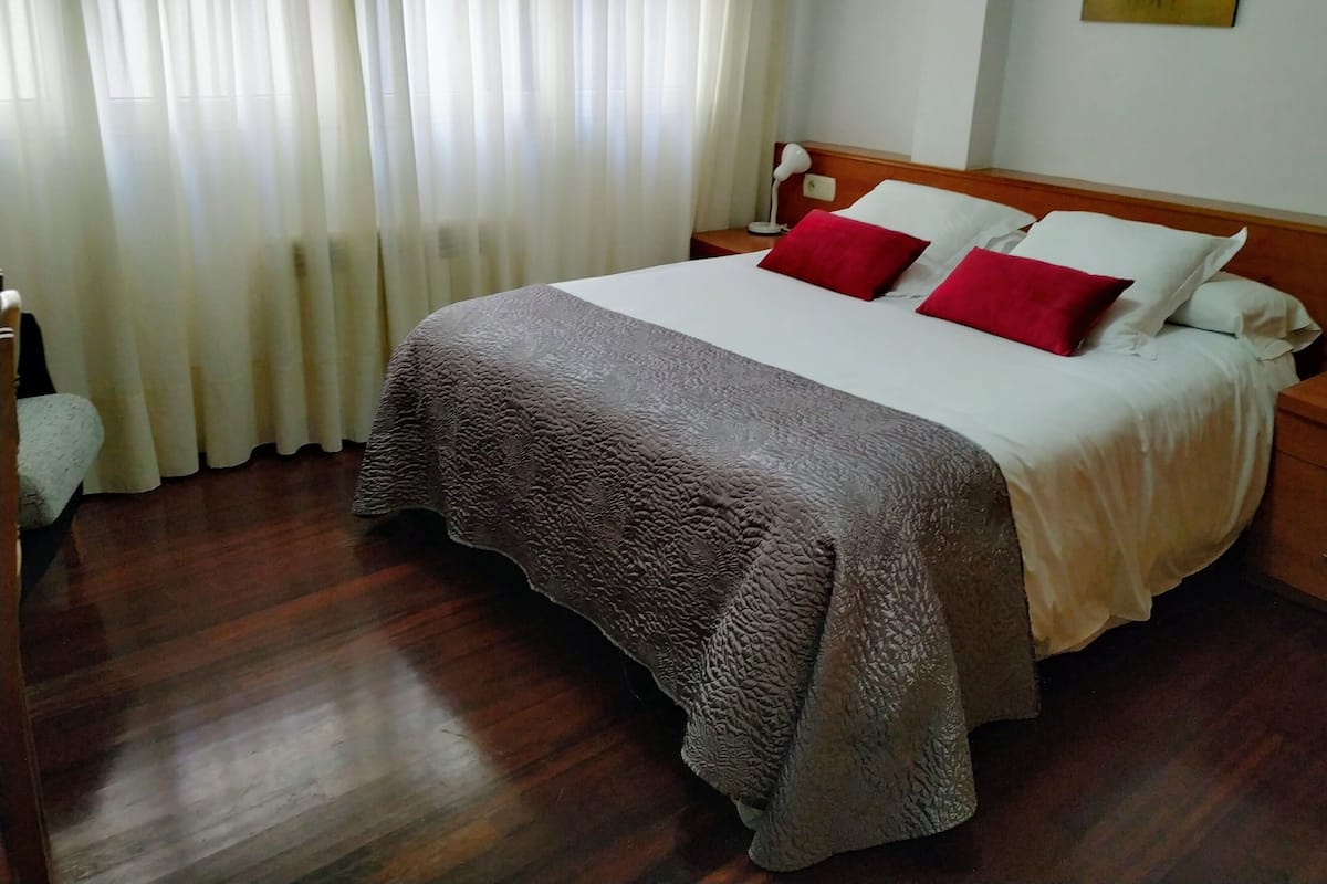 Quarto de hotel com uma cama grande, mesa de cabeceira, abajur e um quadro na parede.