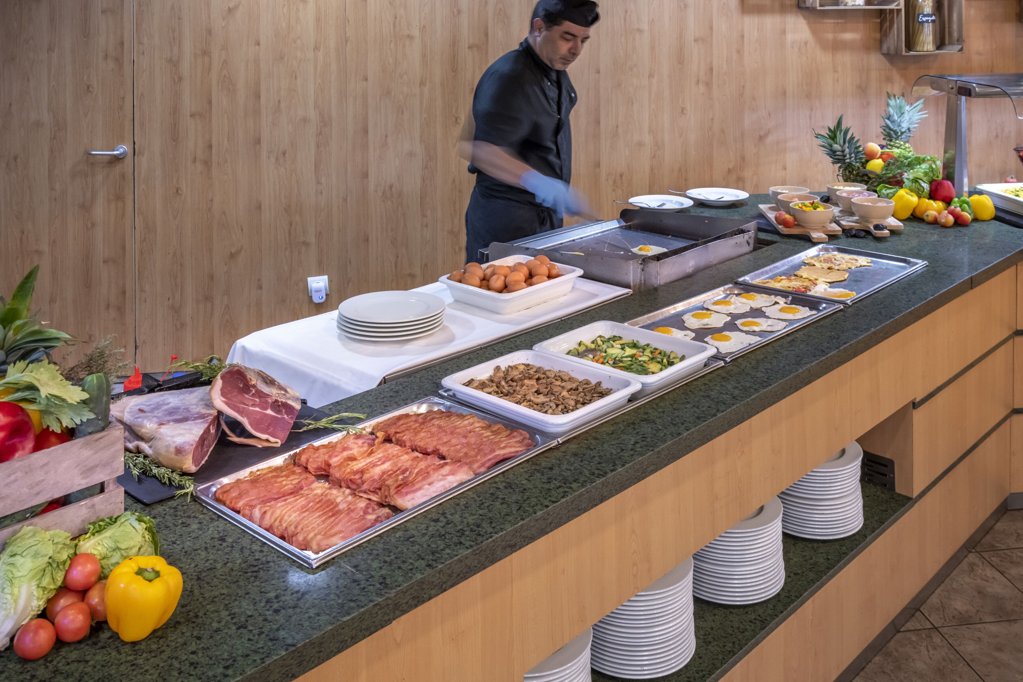 Disposição de buffet com diversos alimentos e um atendente.