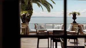 Um terraço com sofá e cadeiras, com vista para um corpo d'água.