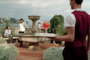 Uma fonte em um jardim com uma pessoa segurando uma bandeja.