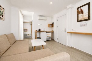Um espaço compacto com sofá, uma mesinha, cozinha compacta e porta para um armário.