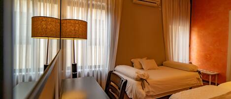 Quarto de hotel com cama, escrivaninha e abajur.