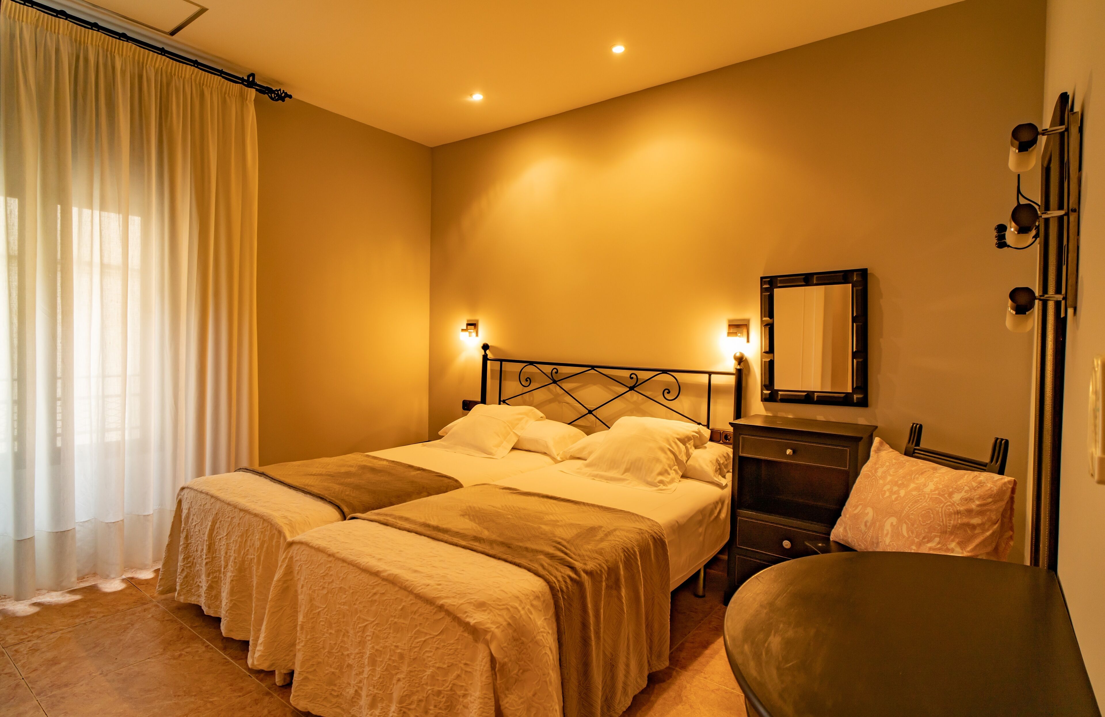 Quarto de hotel com duas camas, uma cômoda, um espelho e uma cadeira.