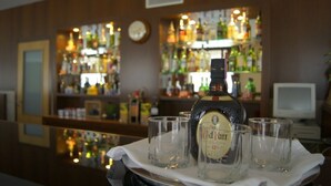 Uma área de bar com uma garrafa de uísque Old Fitzgerald e quatro copos para shot em um tabuleiro.