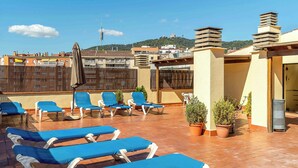 Terraço no telhado com cadeiras de descanso azuis e plantas em vasos.