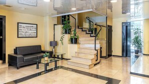 Um hall com escadas, um sofá, uma mesa de centro e um quadro na parede.