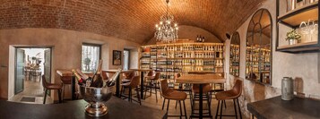Um espaço de bar acolhedor com teto de tijolos, um lustre e uma adega repleta de garrafas.