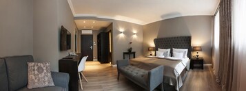 Quarto de hotel moderno com uma cama grande, uma escrivaninha, uma cadeira e um sofá.