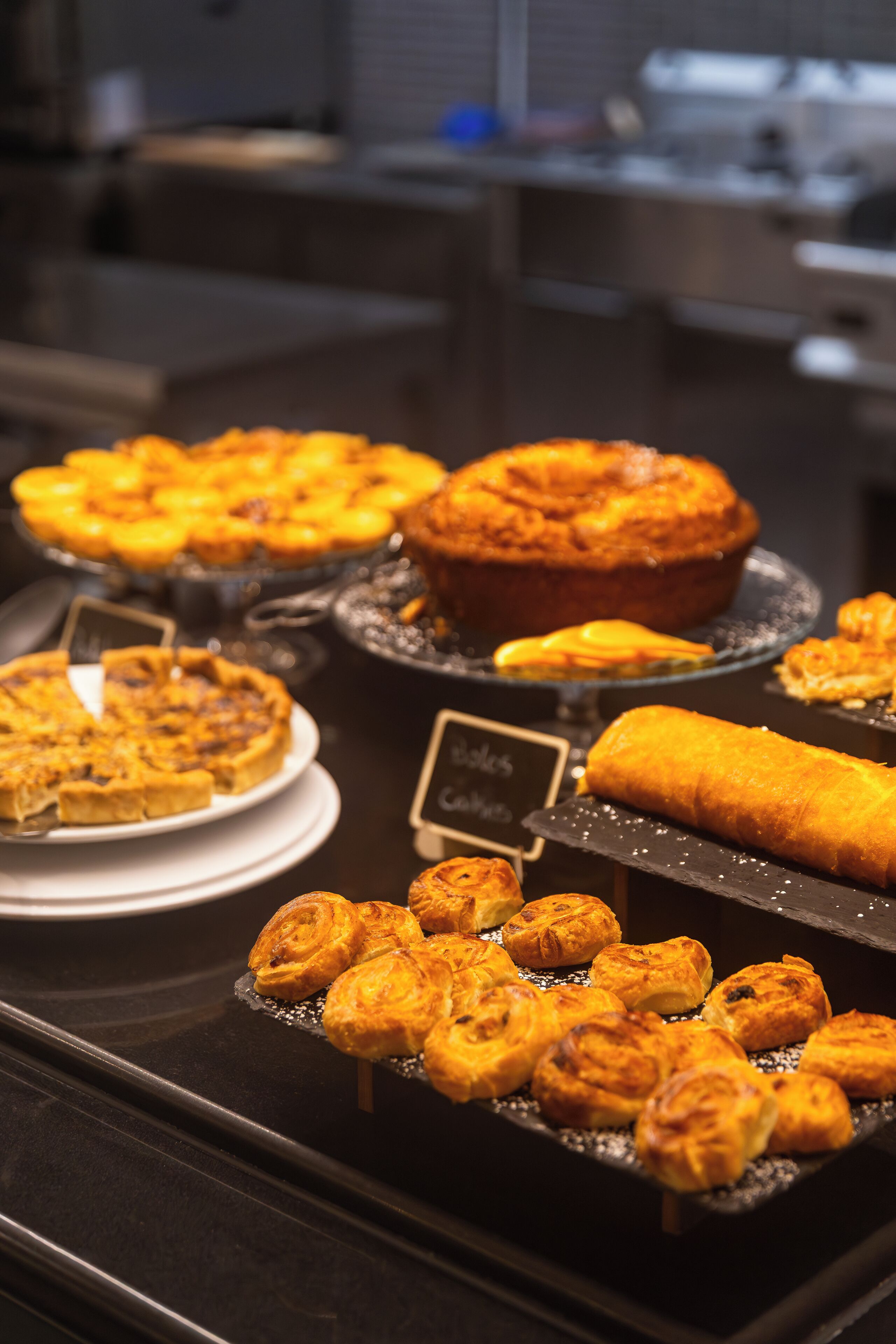 Um buffet com diversos produtos de panificação, incluindo doces, muffins e um grande rolinho de canela.