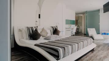 Quarto moderno com uma cama curva, uma pequena escrivaninha e um espaço com chuveiro.