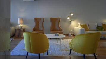 Uma sala de estar moderna com um sofá, duas poltronas, uma mesa de centro e um abajur.