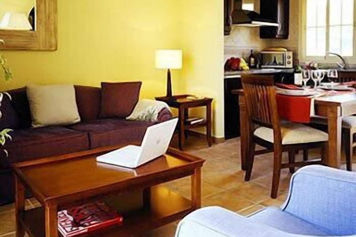 Uma sala de estar com sofá, mesa de centro e uma área de jantar com mesa e cadeiras.