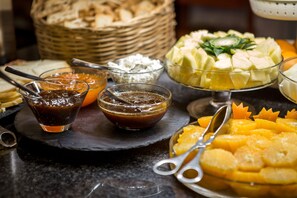 Uma mesa de buffet com diversos alimentos, incluindo frutas, queijos e acompanhamentos.