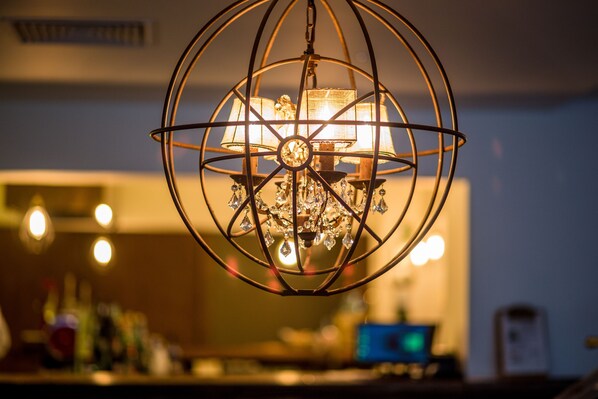Um candelabro esférico com várias fontes de luz e uma lâmpada central, pendurado em um quarto com fundo desfocado.
