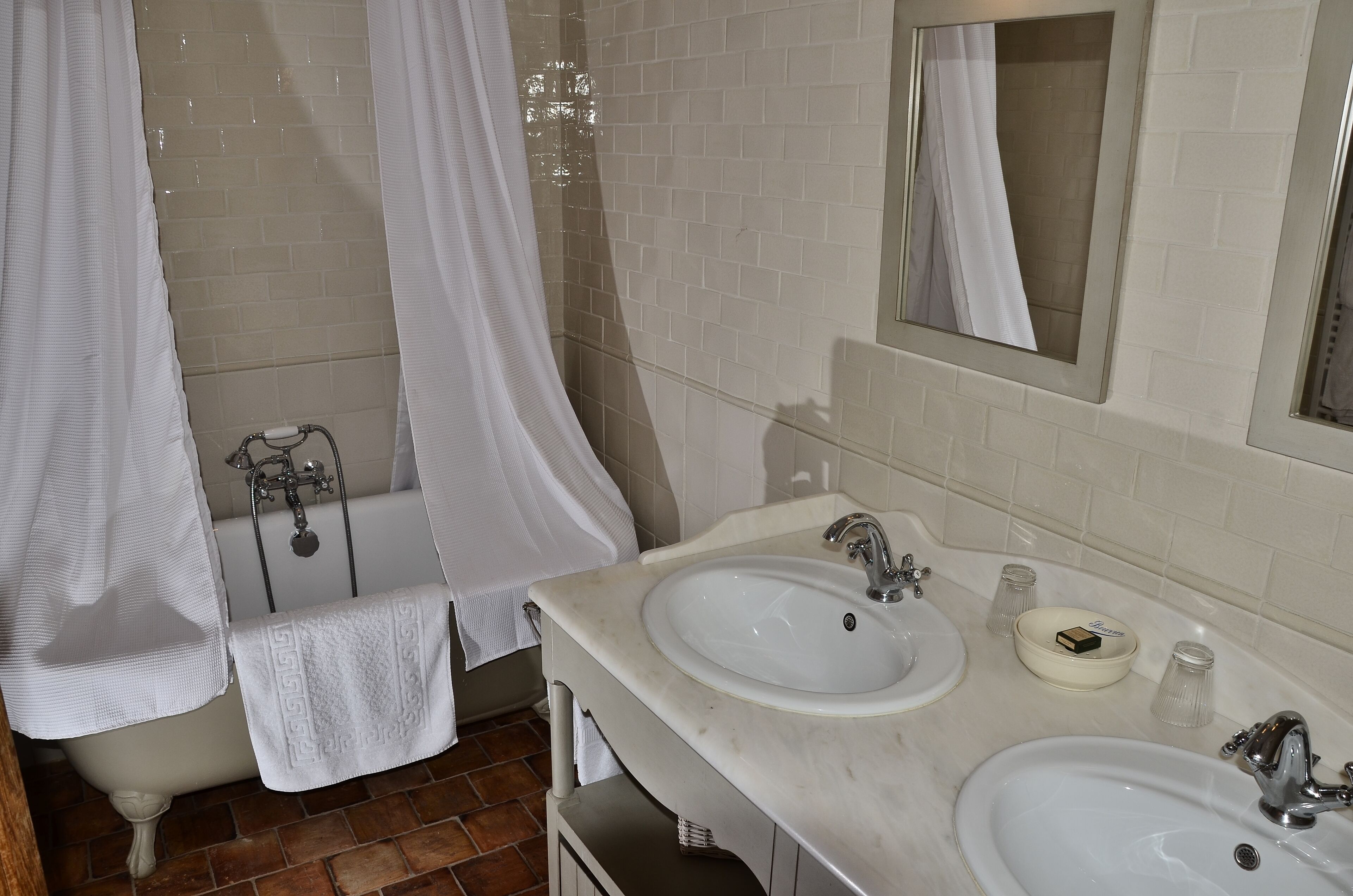 Casa de banho com duas pias, uma banheira e um chuveiro com cortina.