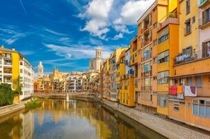 Um canal com edifícios numa margem e uma torre ao fundo.