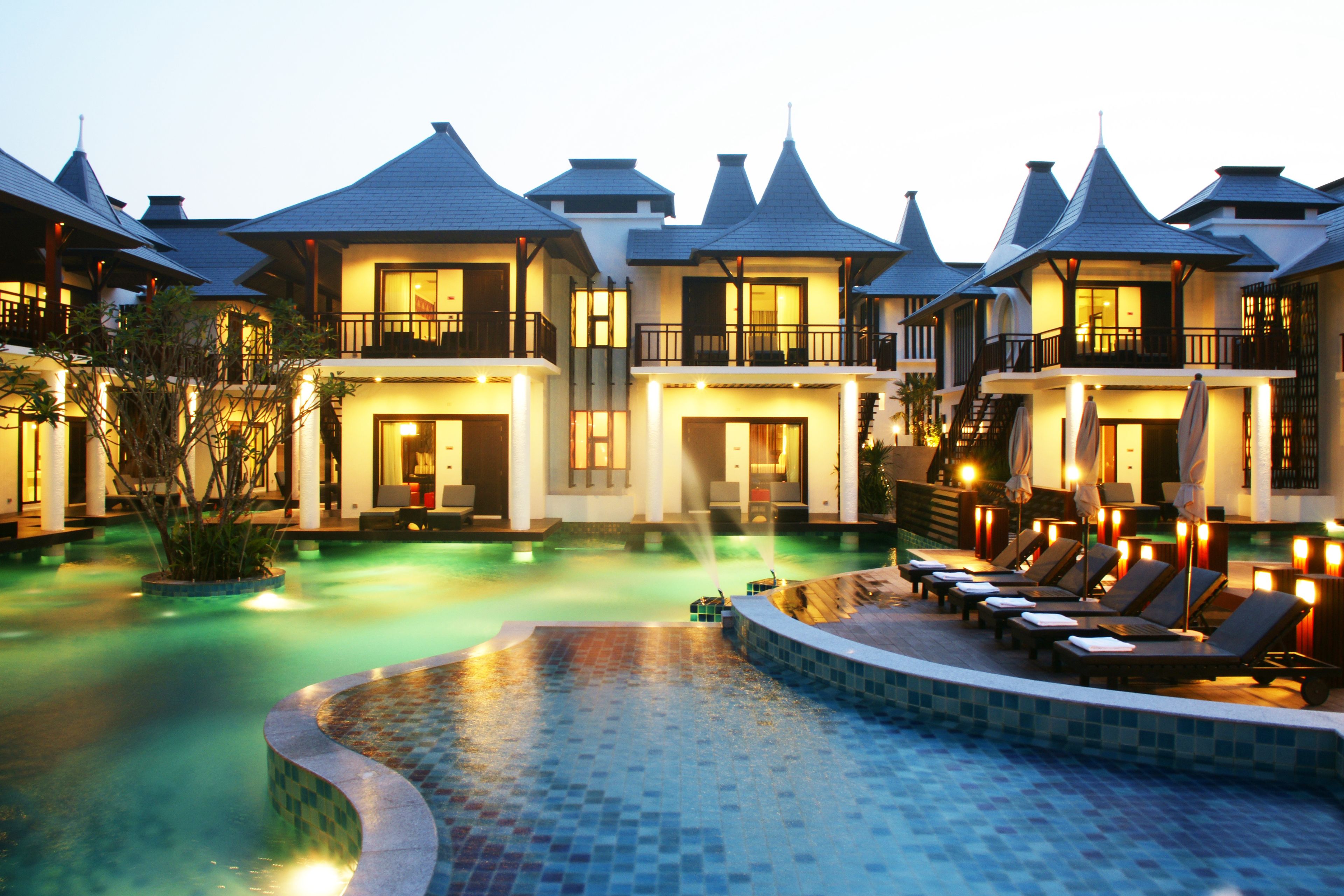 Resort com vários edifícios, piscina e espreguiçadeiras.