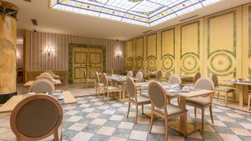 Uma sala de jantar de hotel com chão xadrez, mesas redondas e cadeiras.