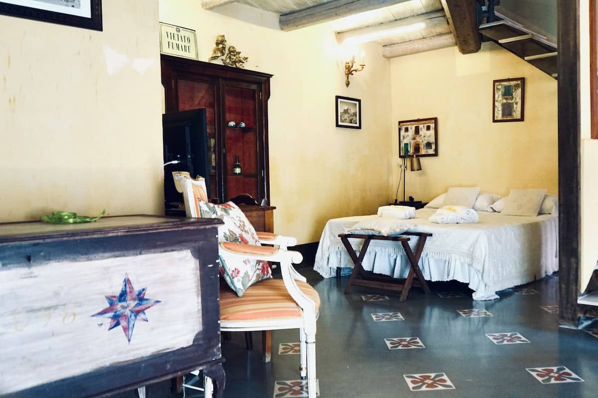 Quarto com cama, cadeira, armário de madeira e escada.