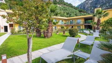 Pátio de hotel com área de estar externa, piscina e vista para as montanhas.
