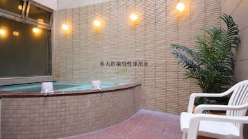 Uma área de spa com hidromassagem, assentos e uma parede com linhas verticais e iluminação.