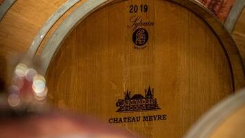 Primeiro plano de barris de madeira com o ano 2019 e o nome Chateau Meyre visíveis.