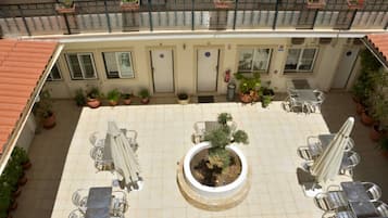 Um pátio com área de estar externa, plantas em vasos e um jardim central.