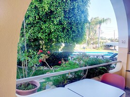 Uma varanda com vista para uma piscina, rodeada por vegetação exuberante e plantas em vasos.
