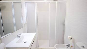 Uma casa de banho moderna com lavatório branco, espelho, sanita e cabine de duche.