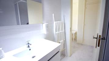 Casa de banho com lavatório branco, espelho e porta-toalhas.