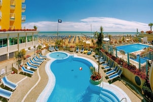 Uma área de piscina em resort com vários espreguiçadeiras e uma piscina central.