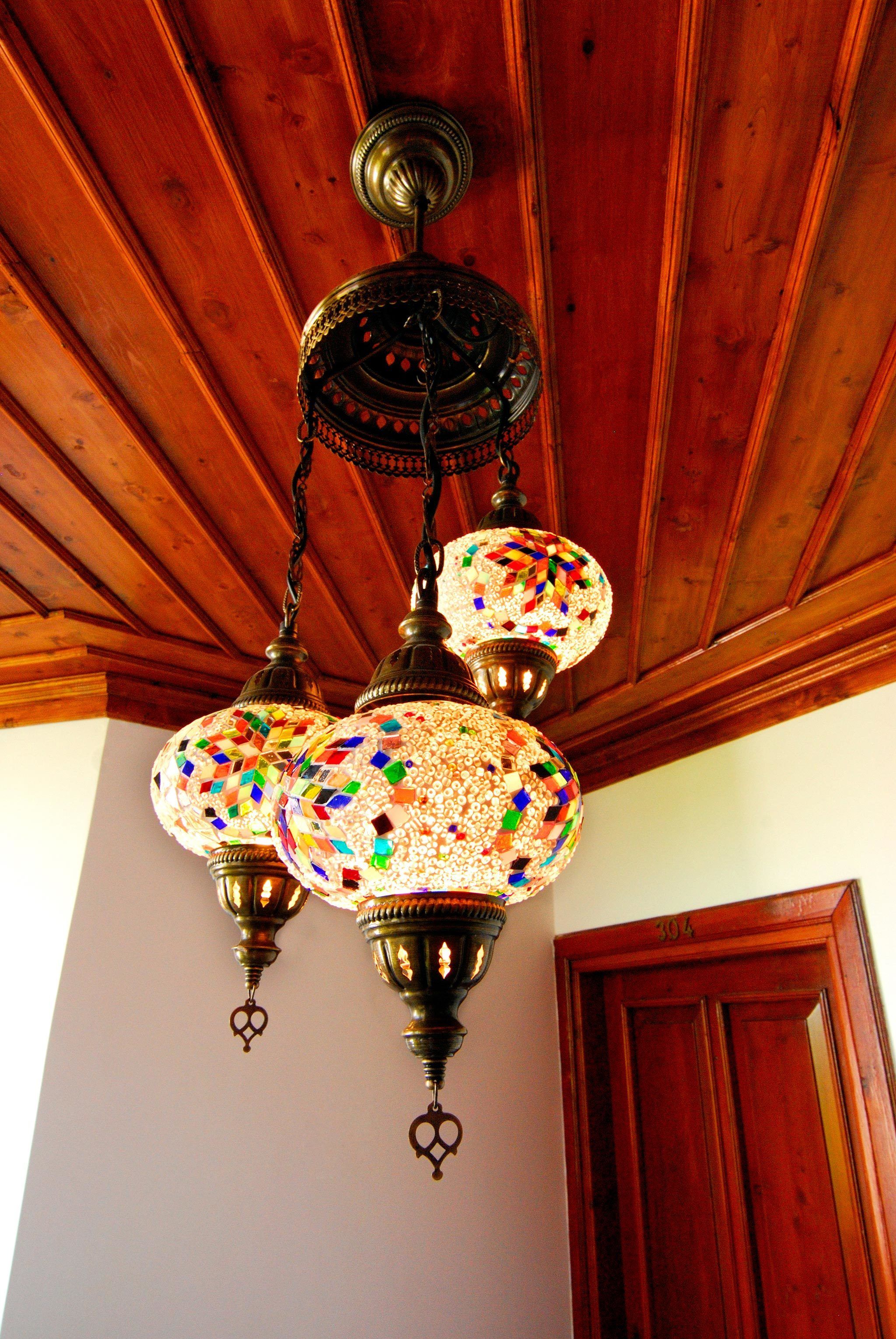 Um candelabro com abajures de vidro mosaicado pendurado no teto de madeira.