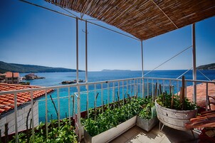 Uma varanda com vista para o mar e colinas ao longe.