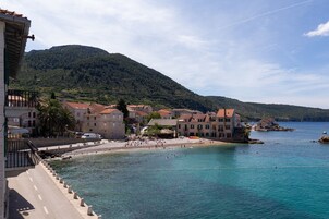 Uma cidade costeira com edifícios ao longo da orla, uma praia e uma montanha ao fundo.