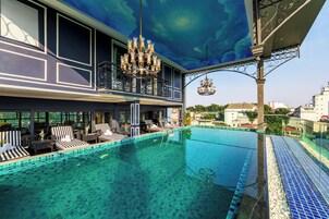 Piscina infinita no terraço com espreguiçadeiras, área de bar e teto decorativo.