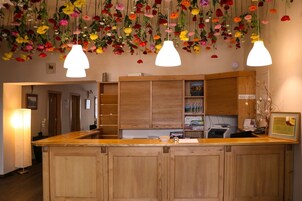 Uma área de recepção com balcão de madeira, decorações florais pendentes e iluminação pendurada.