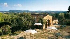 Uma vila com alpendre, rodeada por vegetação exuberante e colinas ao fundo.