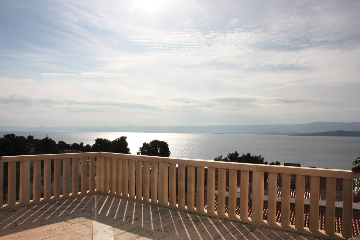 Varanda com vista para o mar e montanhas ao longe.