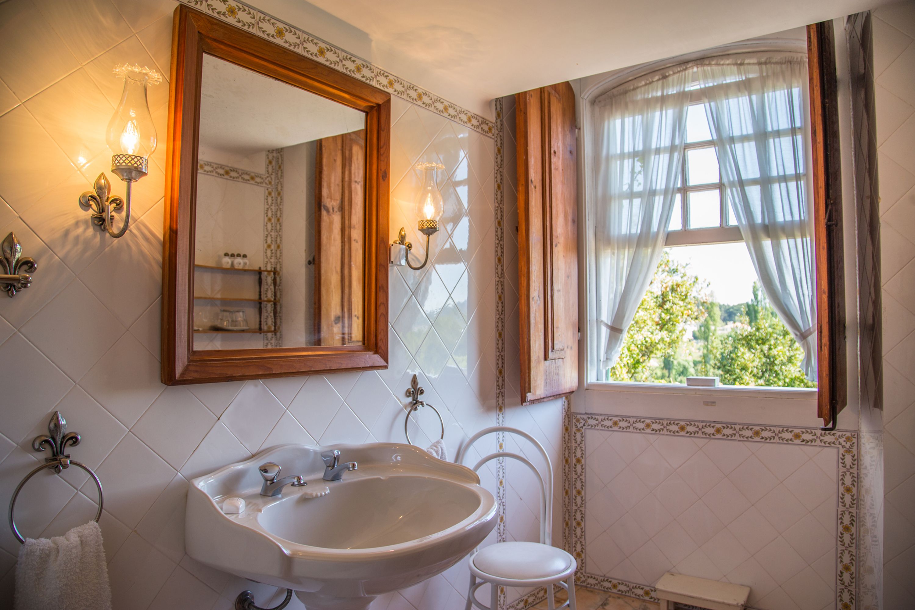 Casa de banho com uma pia grande, um espelho e uma janela com cortinas.