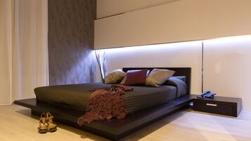 Quarto moderno com cama grande, mesa de cabeceira e criado-mudo.