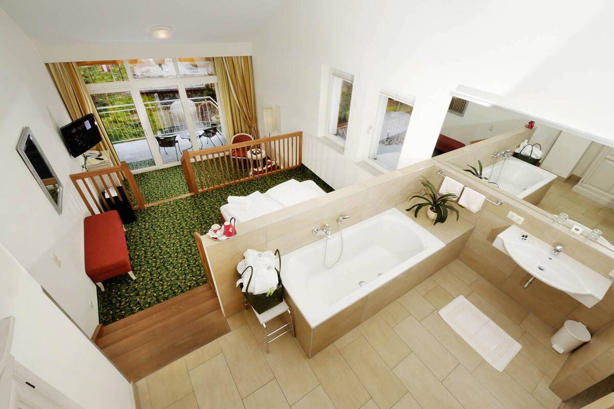 Uma casa de banho de hotel moderna com uma banheira grande, duas pias e um espelho.