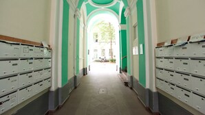 Um corredor com paredes verdes e brancas, chão de azulejos e fileiras de caixas de correio em ambos os lados.