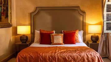 Quarto de hotel com uma cama grande, duas luminárias de cabeceira, um quadro na parede e uma janela com cortinas.