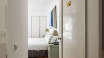 Quarto de hotel com cama, abajures, mesa de cabeceira e um quadro na parede.